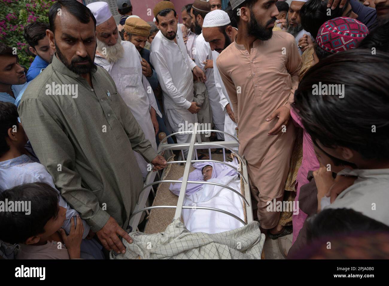 People gather around a body of child, who died in a stampede, during ...