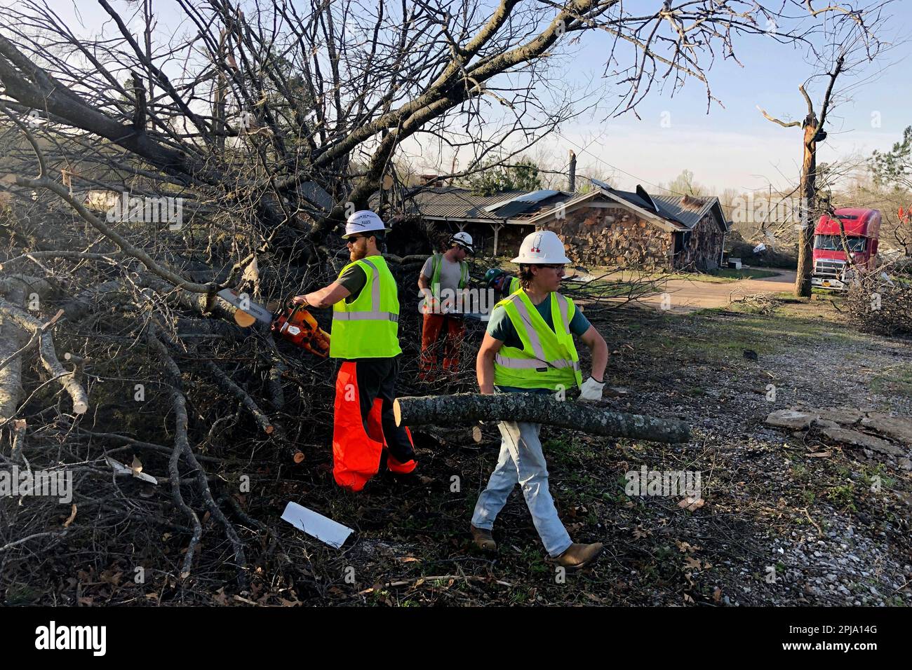 Workers cut fallen trees along a road leading to Wynne, Ark., on ...
