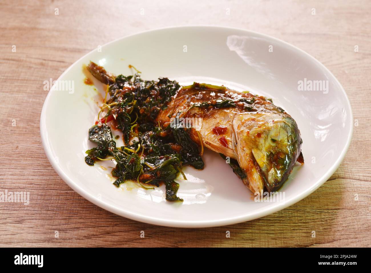 spicy boiled mackerel topping basil in chili sauce on plate Stock Photo ...