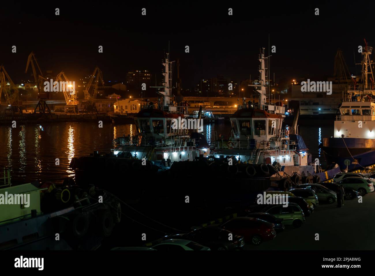 a night port with tugboats at the pier and dissected cars on the pier ...