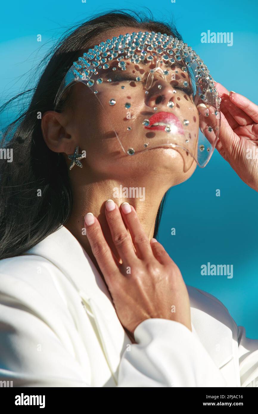 A brunette girl in a white suit with a transparent mask on her face ...