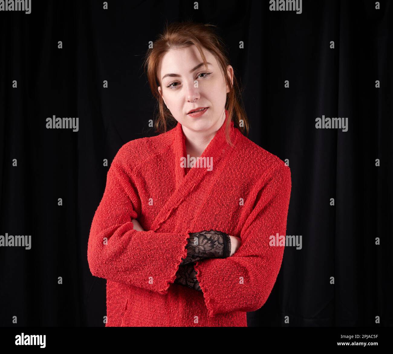 Young Caucasian woman standing with faint smile, arms folded, wearing ...