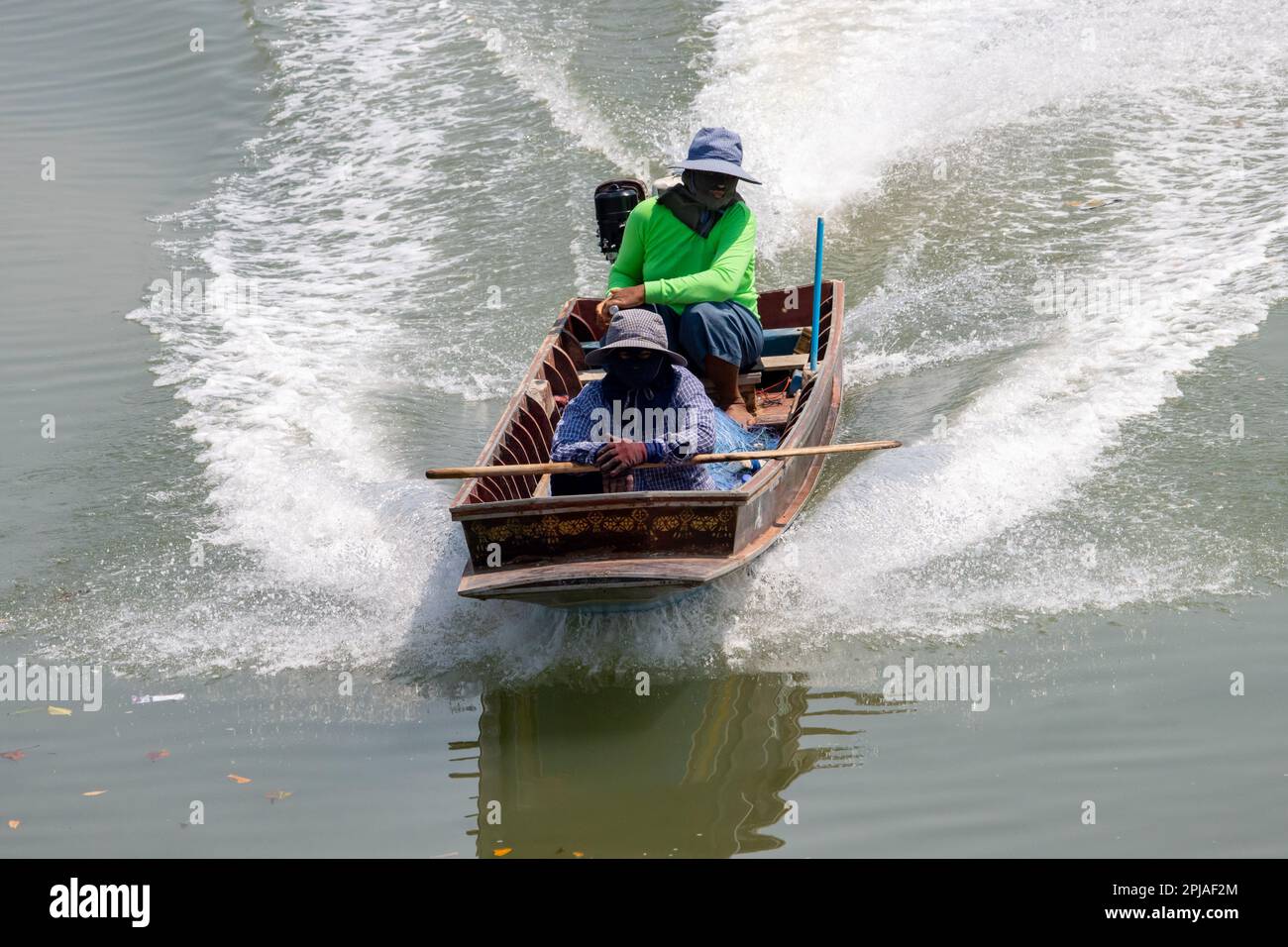 A couple rides a boat with fishing net in a water canal on the ...