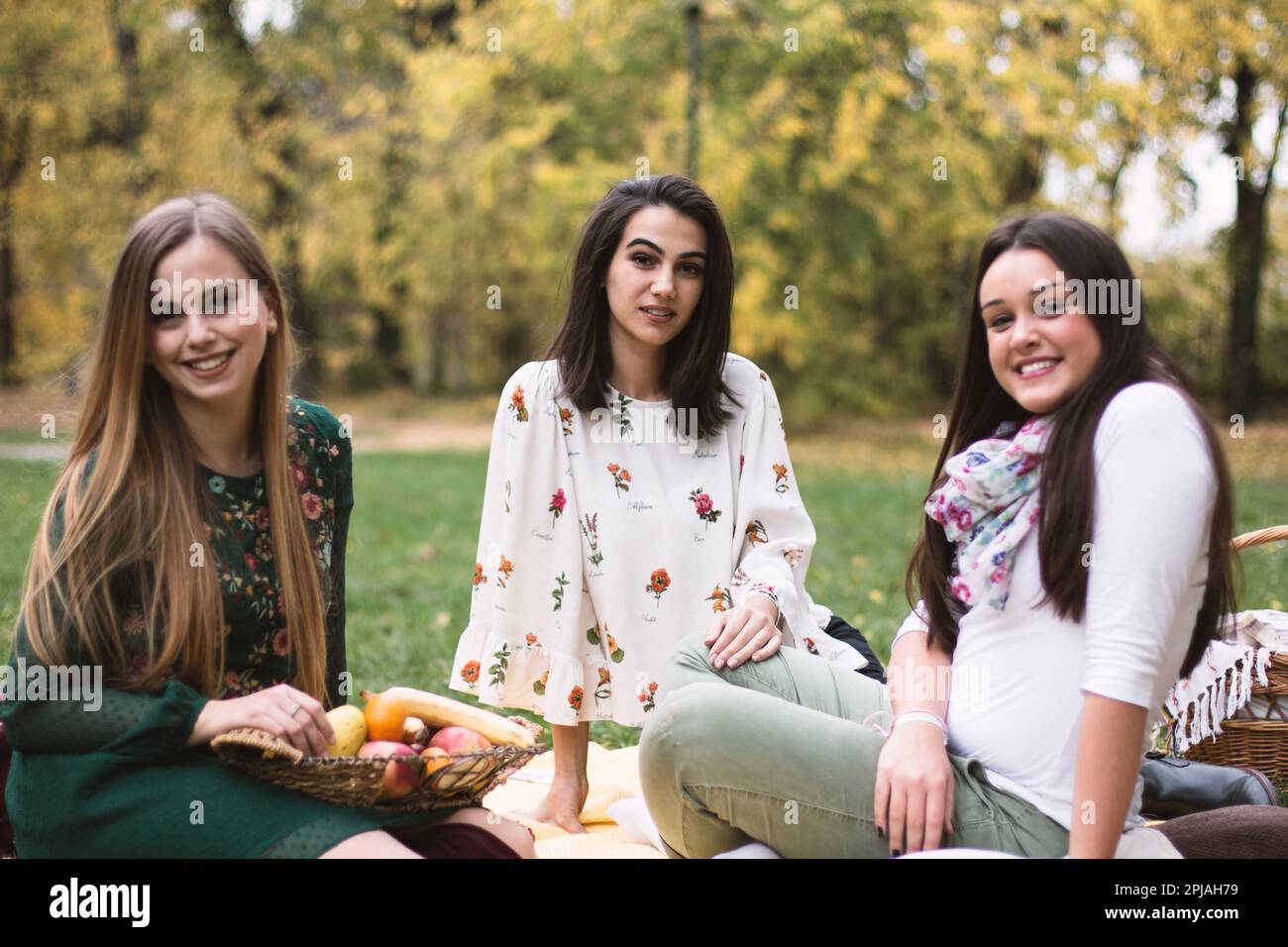 Group of three women on a fun fall picnic in the park, having a good ...