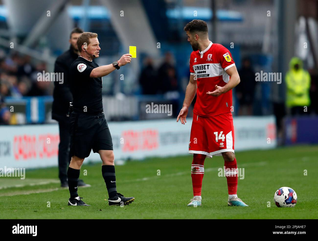 Referee John Busby shows a yellow card to Middlesbrough's Tommy Smith ...