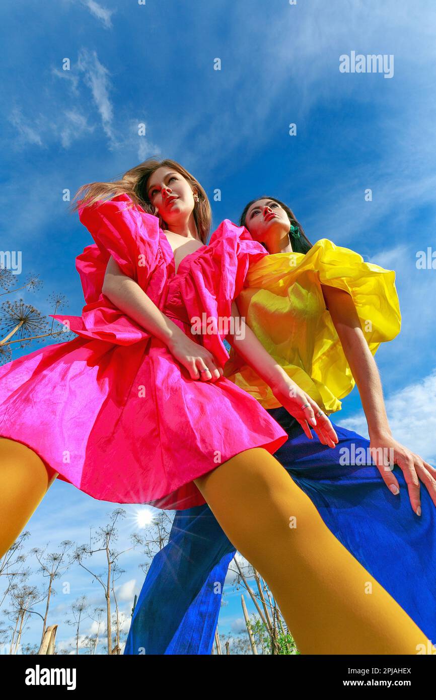 Two models in bright outfits pose against the background of nature ...
