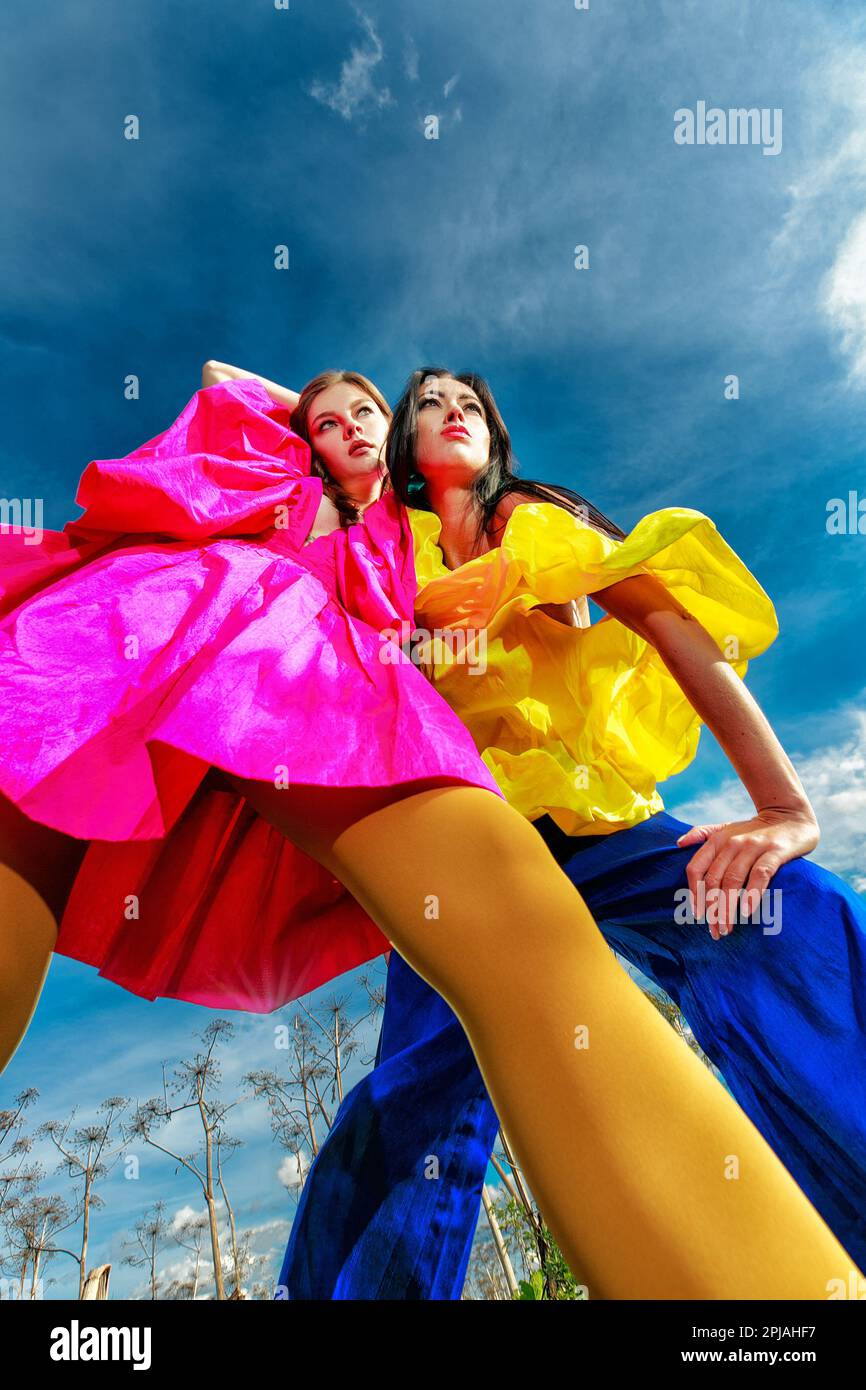 Two models in bright outfits pose against the background of nature ...