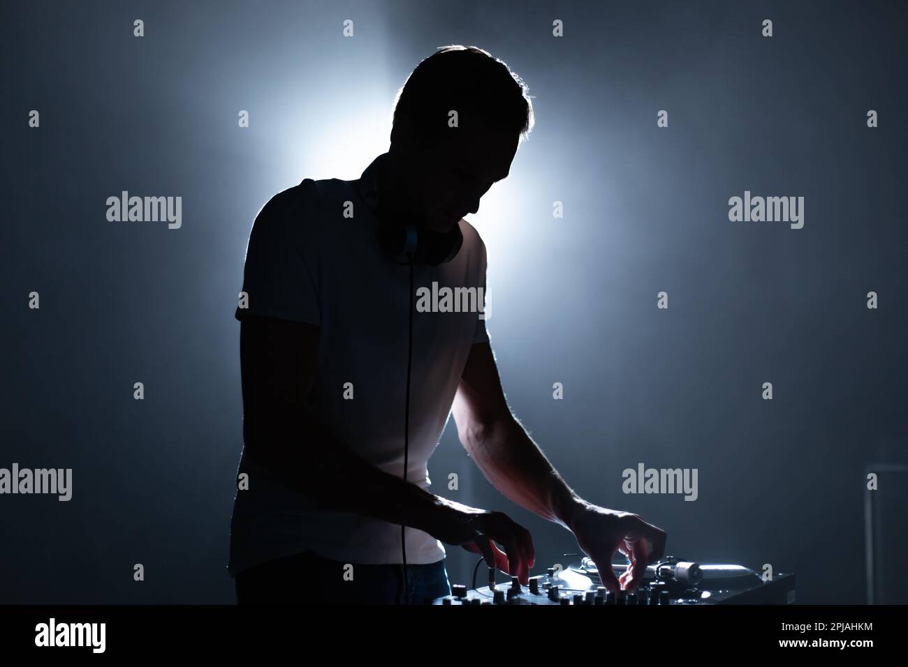 Silhouette of a DJ performing on party in night club. Cool young man ...