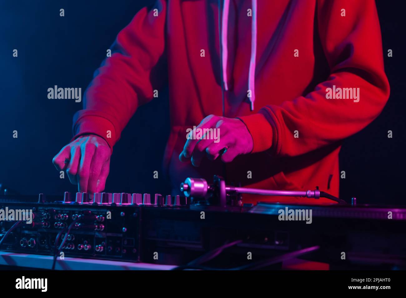 Club DJ adjusting volume on a sound mixer device in night club. Close ...