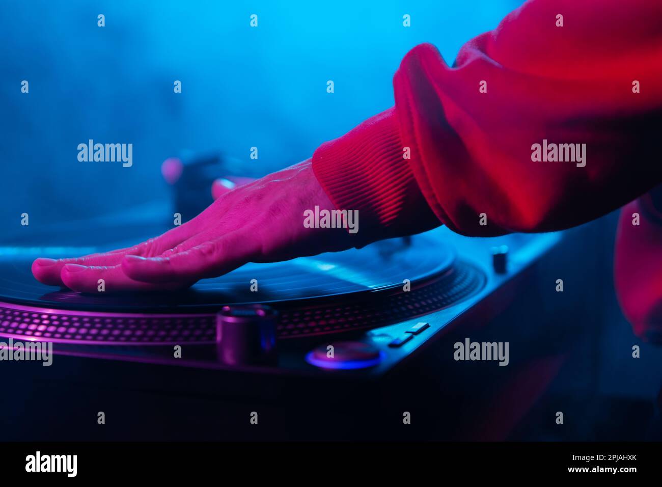 Hand of a hip hop DJ scratching vinyl record on turntable in close up ...