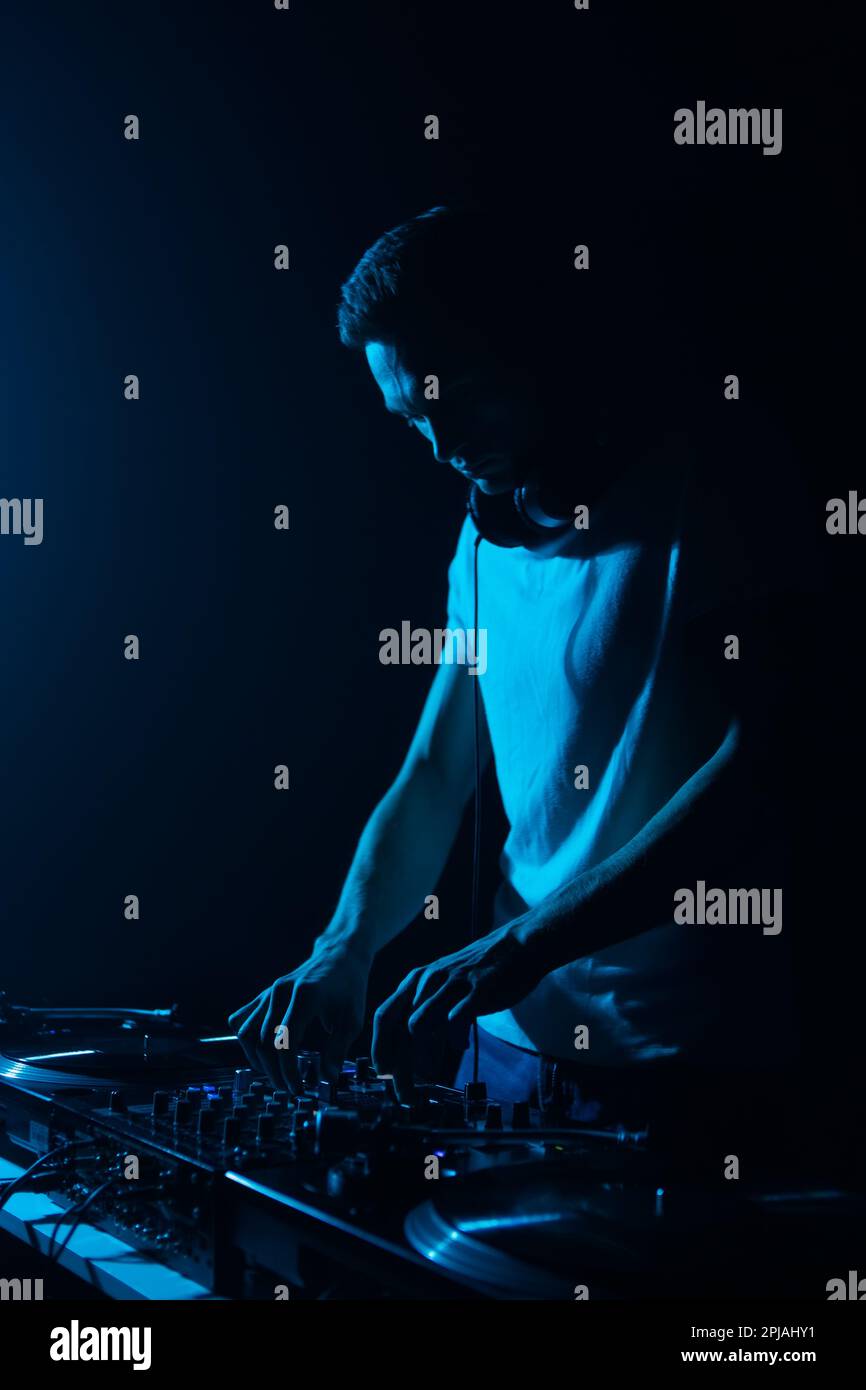 Silhouette of techno DJ playing music in night club. Cool young white ...