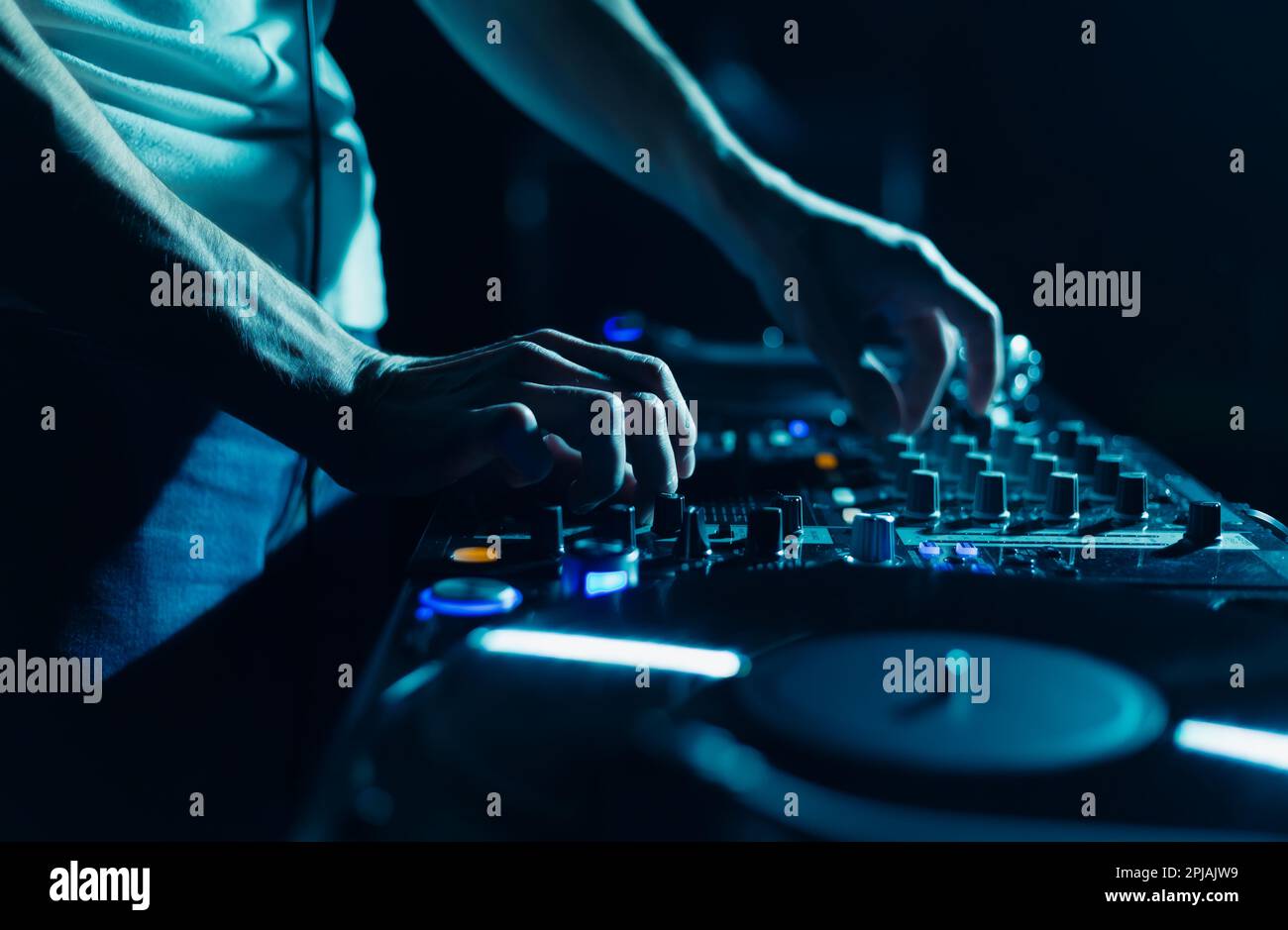 Techno party DJ playing music with sound mixer and turntables. Club ...