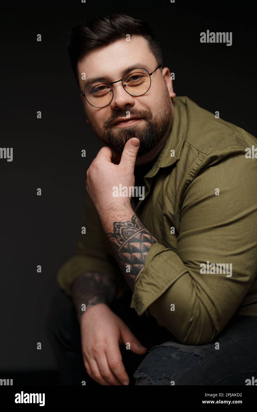 Pensive bearded man looking at camera and touching chin Stock Photo - Alamy