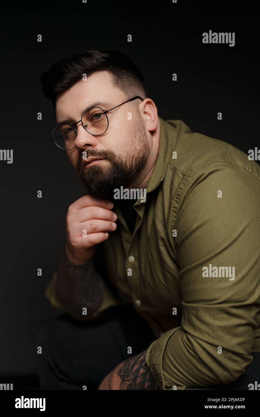 Pensive bearded man looking at camera and touching chin Stock Photo - Alamy