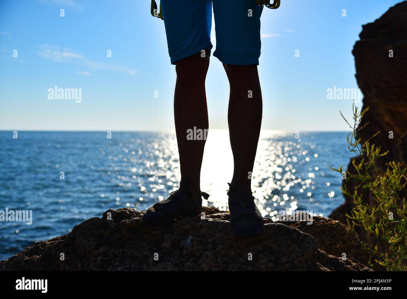 foot climber on a cliff, sunsen in ocean on background Stock Photo - Alamy