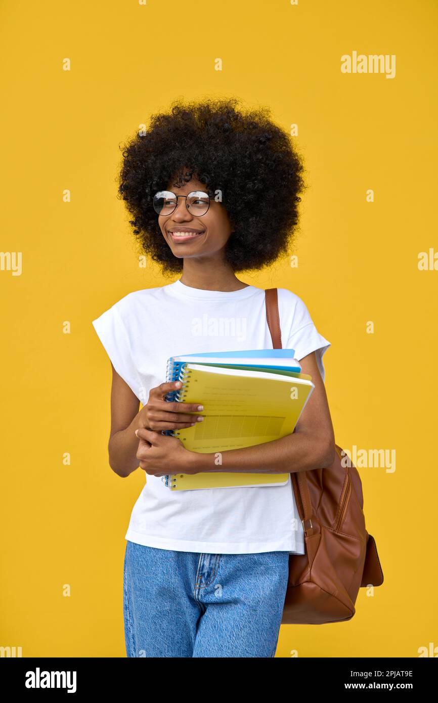 Vertical portrait of a smart student looking aside on yellow background ...
