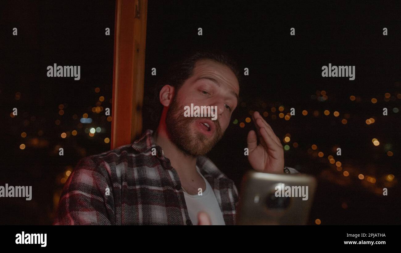 Bearded, long-haired handsome young man having a video call in a ...