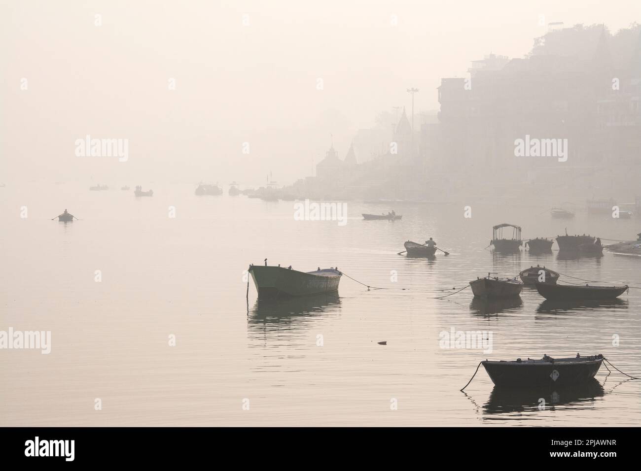A misty winter morning view of boats on the Ganges in Varanasi, India ...