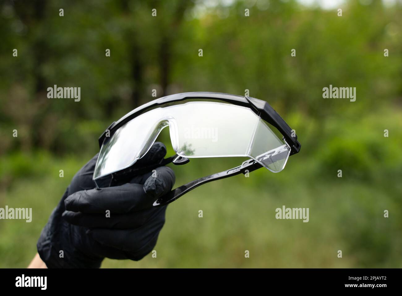 hand in black medical gloves holds medical goggles on an isolated ...