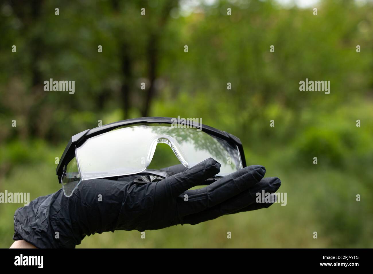 hand in black medical gloves holds medical goggles on an isolated ...