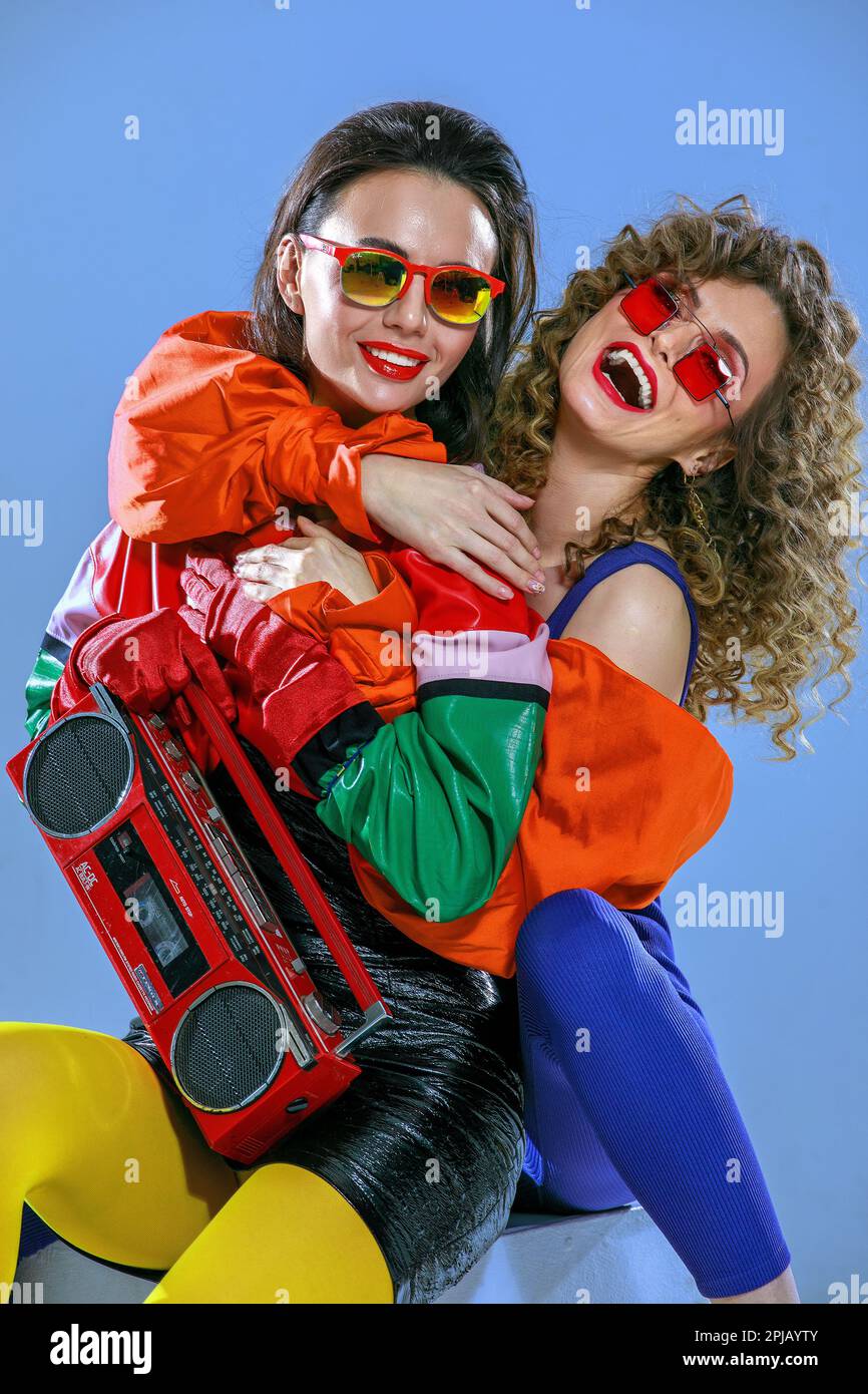 Two young girls in bright outfits pose in the studio Stock Photo - Alamy