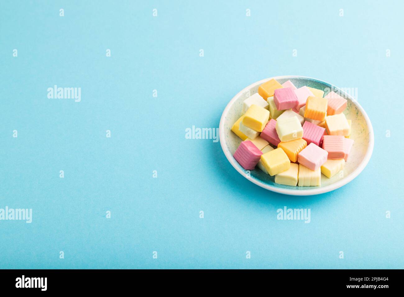 Various fruit jelly chewing candies on plate on blue pastel background ...