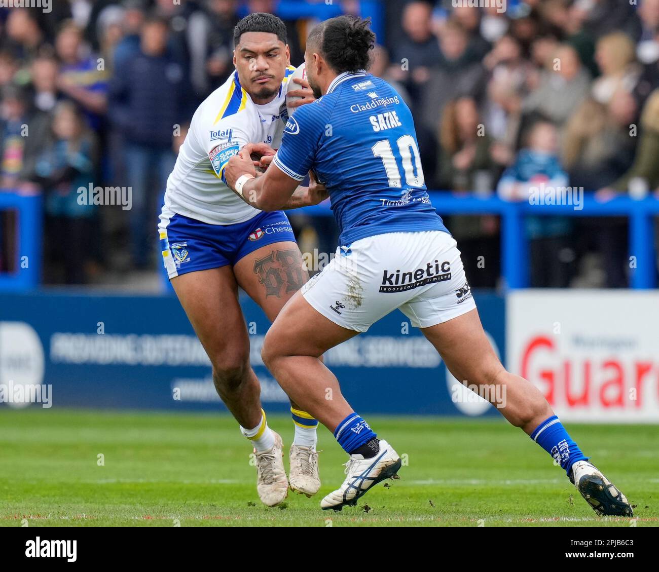 Tom Mikaele #18 of Warrington Wolves runs at Chris Satae #10 of Hull FC ...