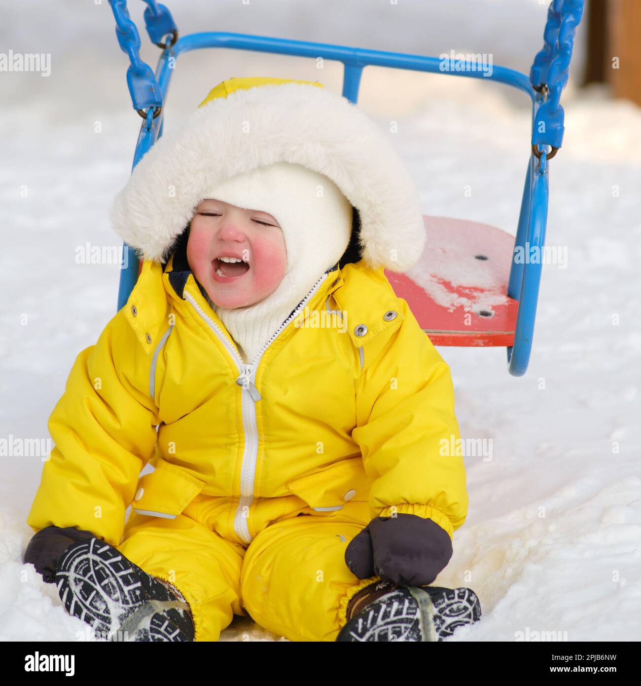 Toddler baby fell off the swing into the snow at the winter playground ...
