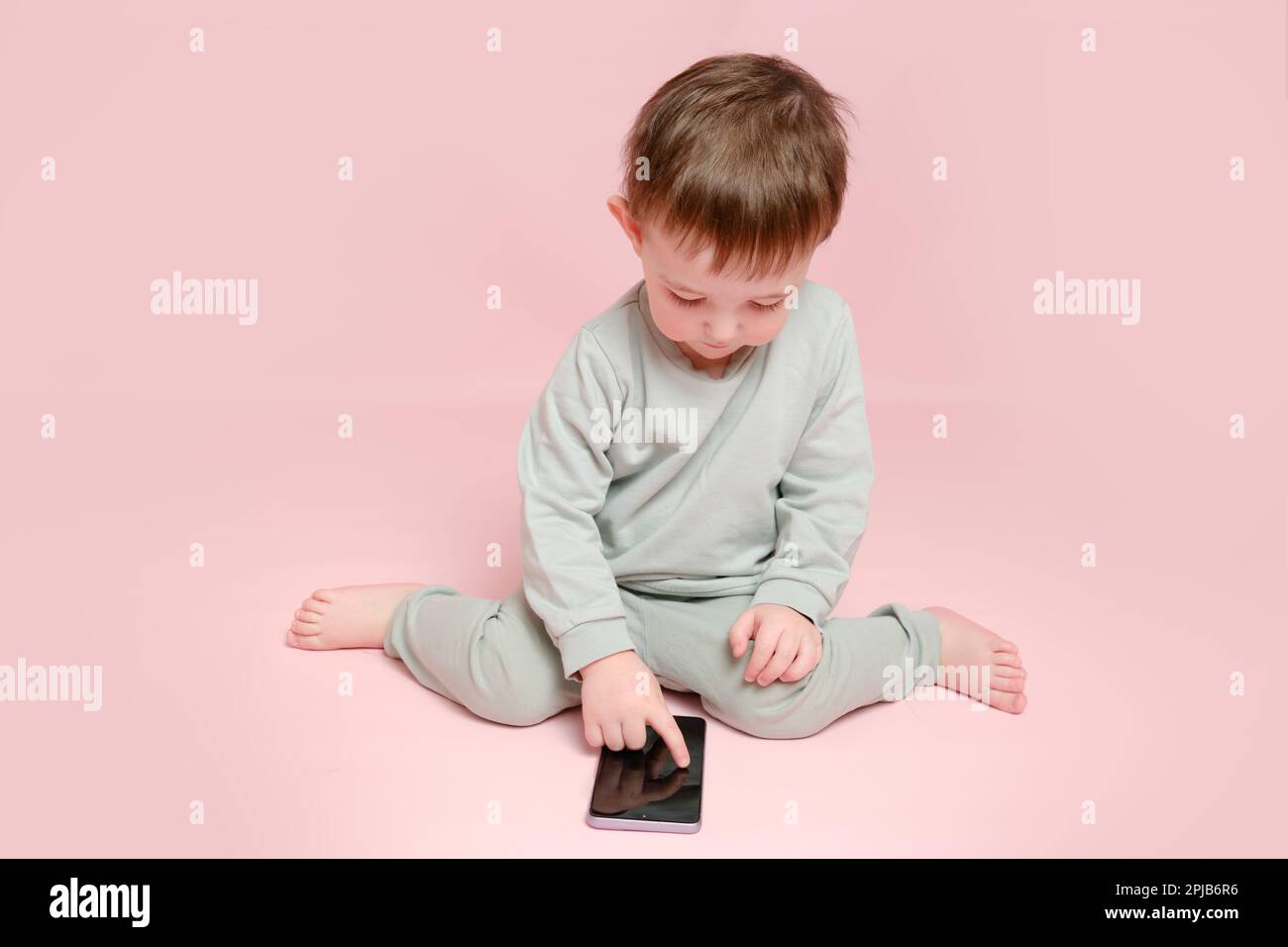 Happy toddler baby with mobile phone on studio pink background. Child ...
