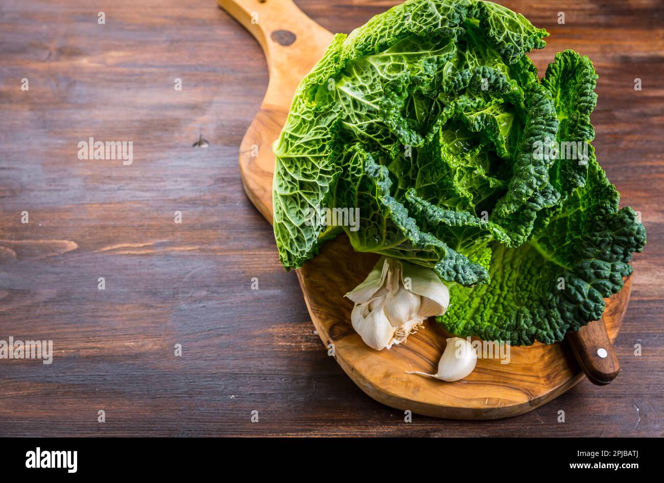 Fresh raw savoy cabbage with garlic and knife on wooden background ...