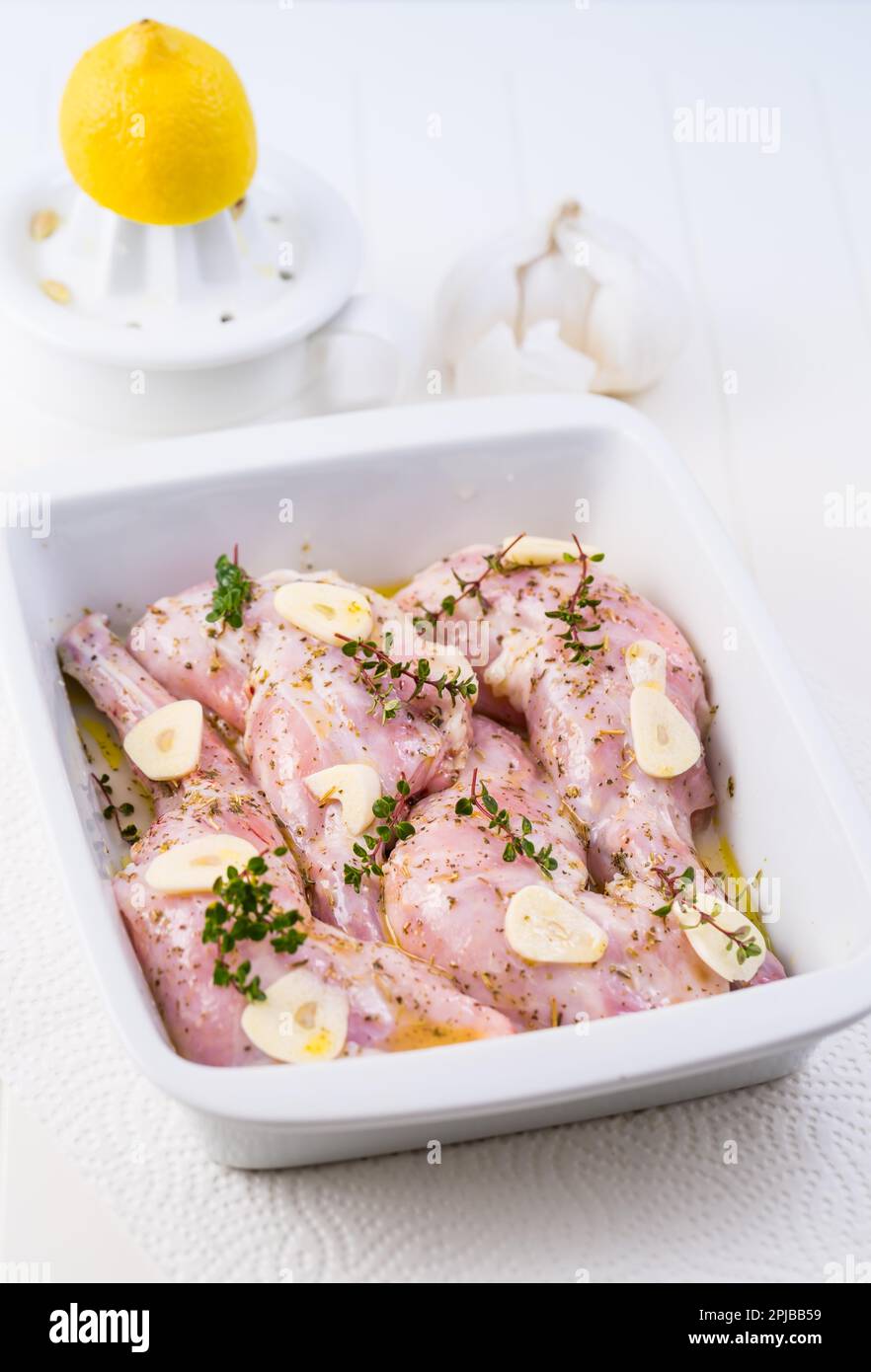 Marinated rabbit legs with lemon, garlic and herbs in the casserole ...