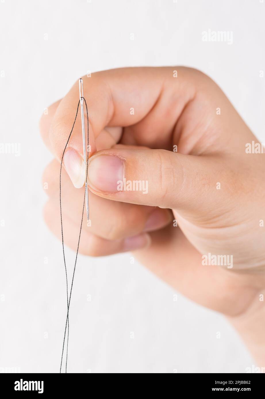 Detail of hand holding needle with thread on white background Stock ...