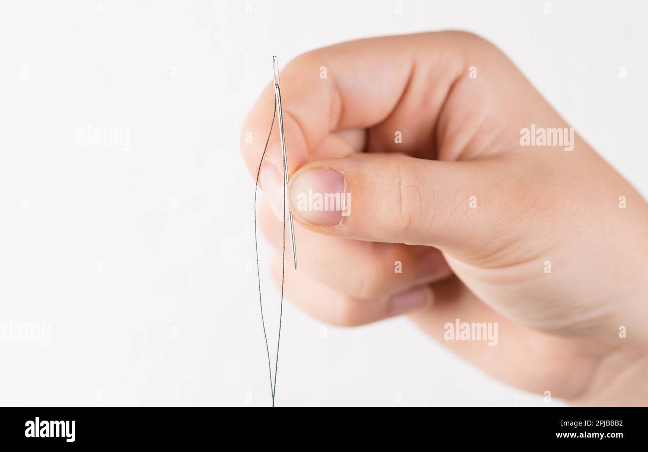 Detail of hand holding needle with thread on white background Stock ...