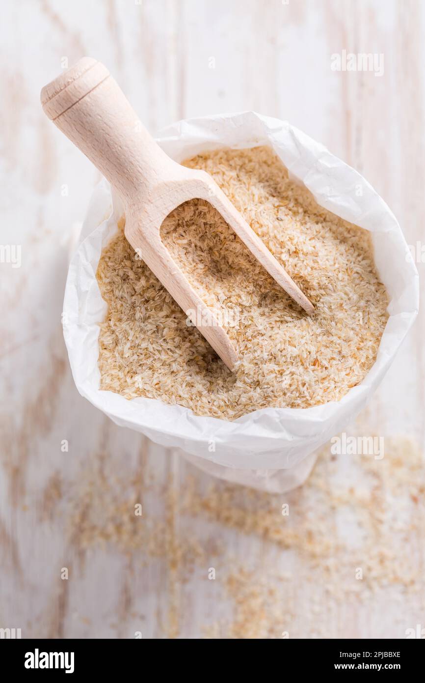 Heap of psyllium (Plantago ovata) husk in small bag on wooden table ...