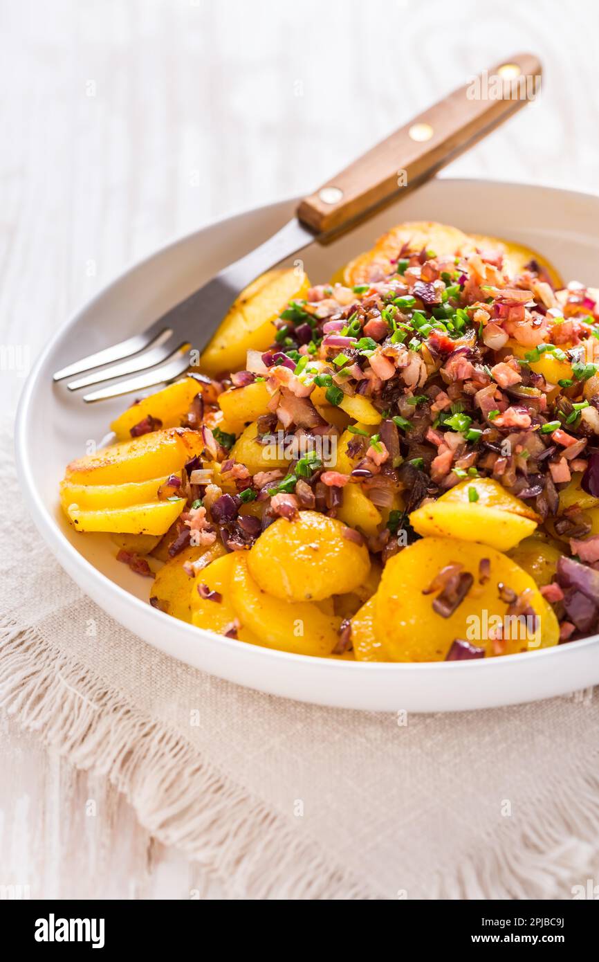 German fries - fried potatoes with bacon and onion topping on plate ...