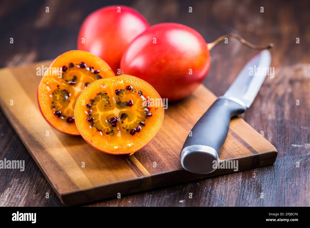 Organic tamarillo (Solanum betaceum) (tree tomato) on cutting board ...