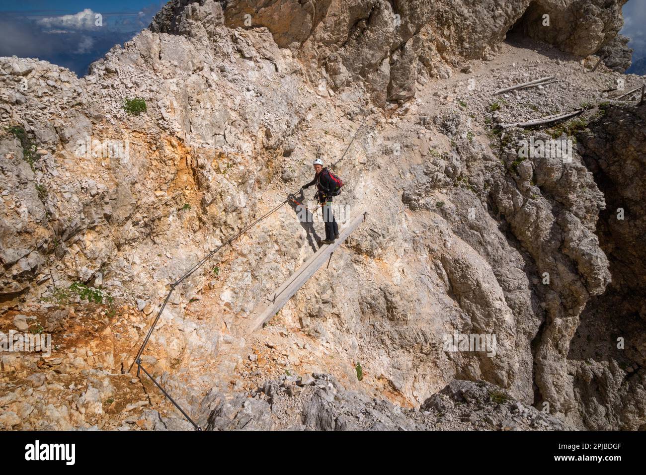 Tourist crossing the via ferrata trail with equipment in the dolomites ...
