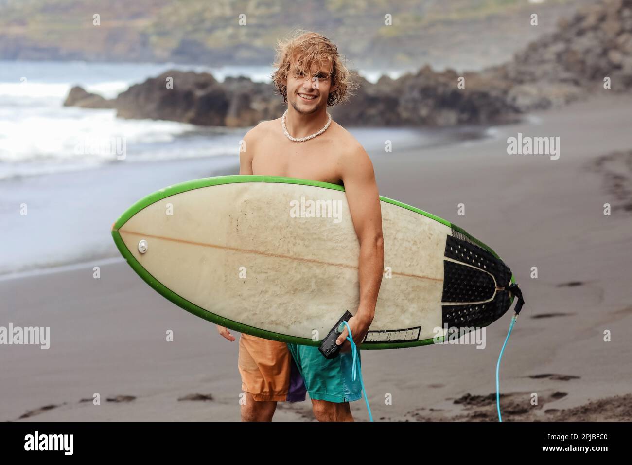 Handsome fit young blond man with mock up surfboard waits for wave to ...