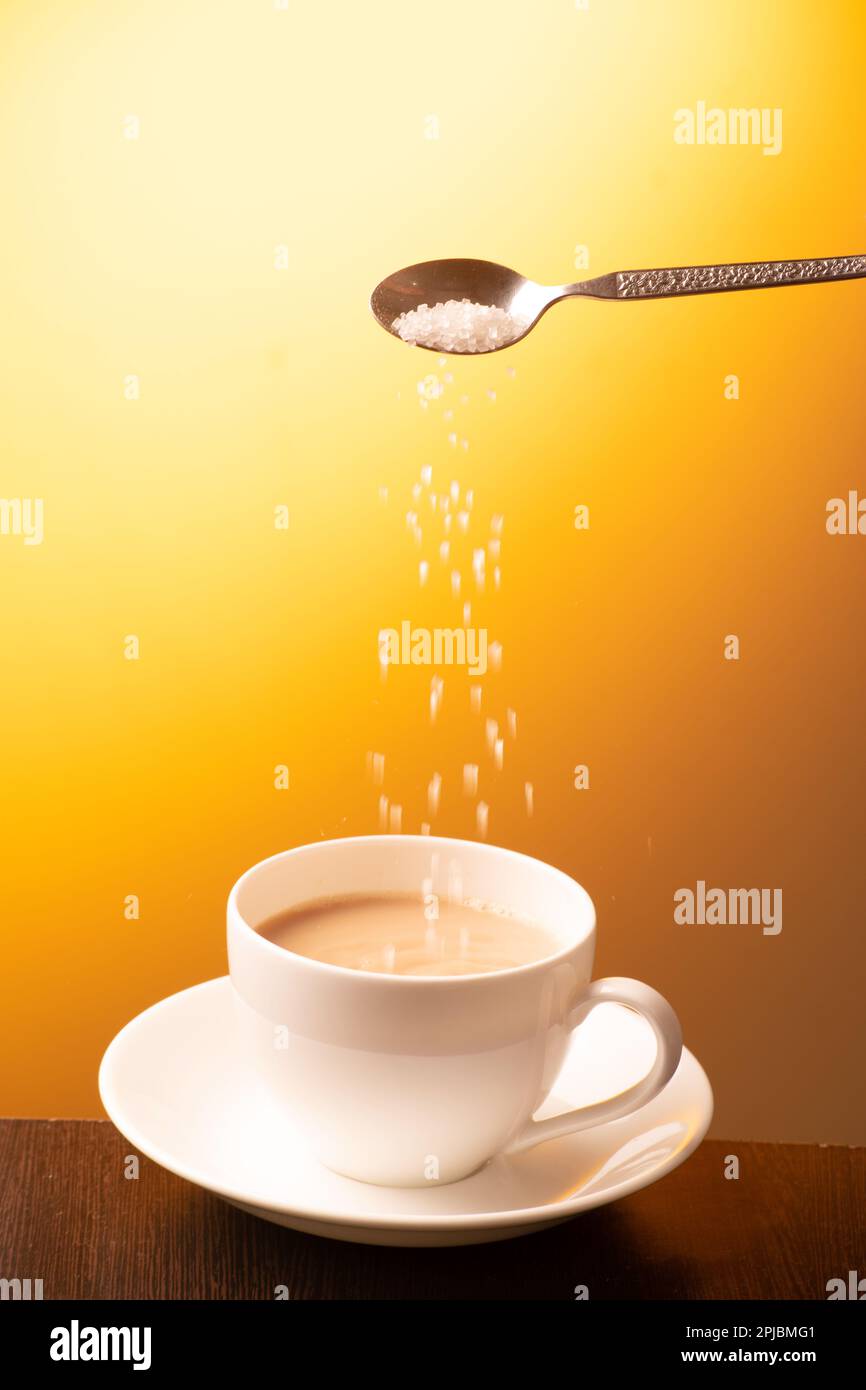 Sugar pouring in cup of tea Stock Photo - Alamy