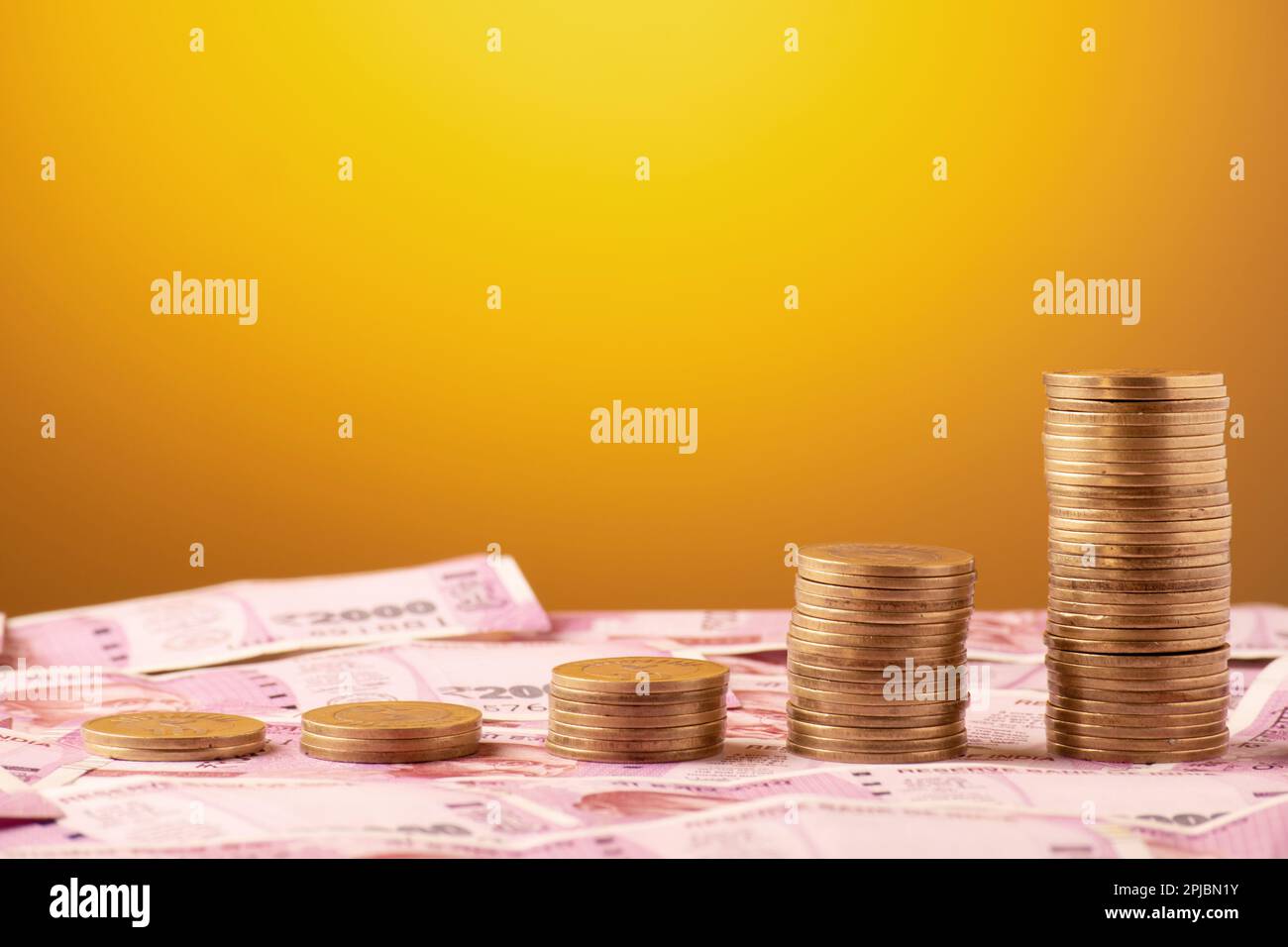 Indian currency coin stack with rupee note on yellow background Stock ...