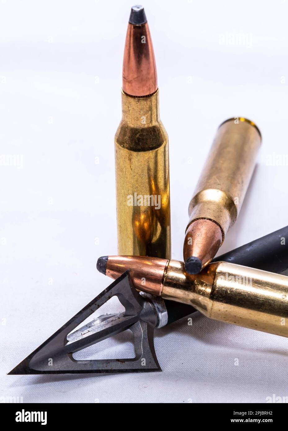 Three different caliber hunting rifle bullets with an arrow broad head ...