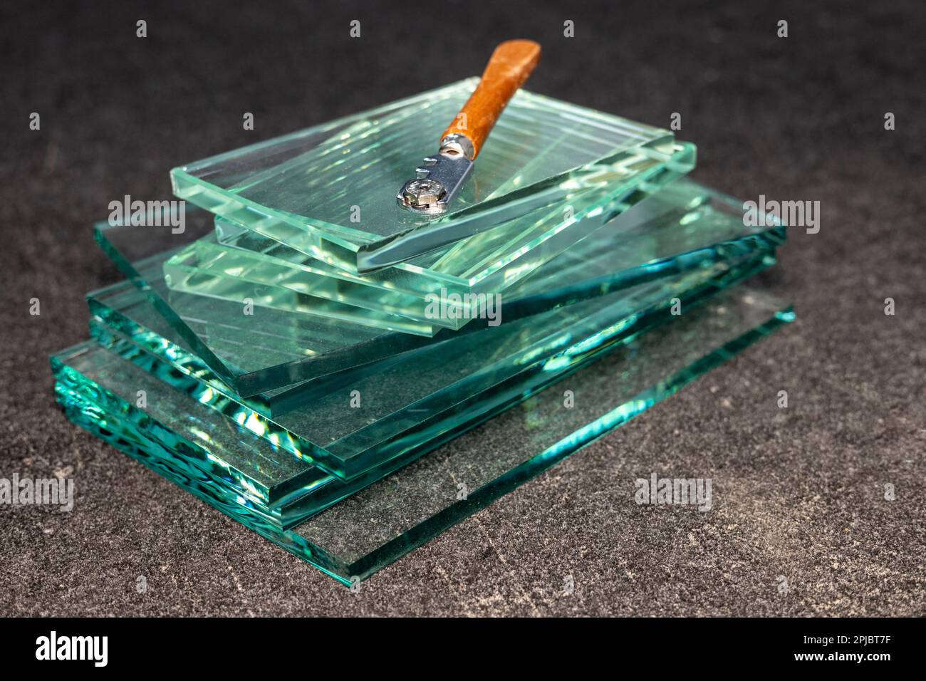 Pieces of thick glass stacked and a specialized glass cutter, Concept ...