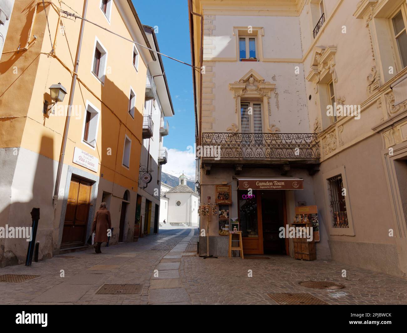 Lady walks by on a quaint street in the town of Aosta with the Santa ...