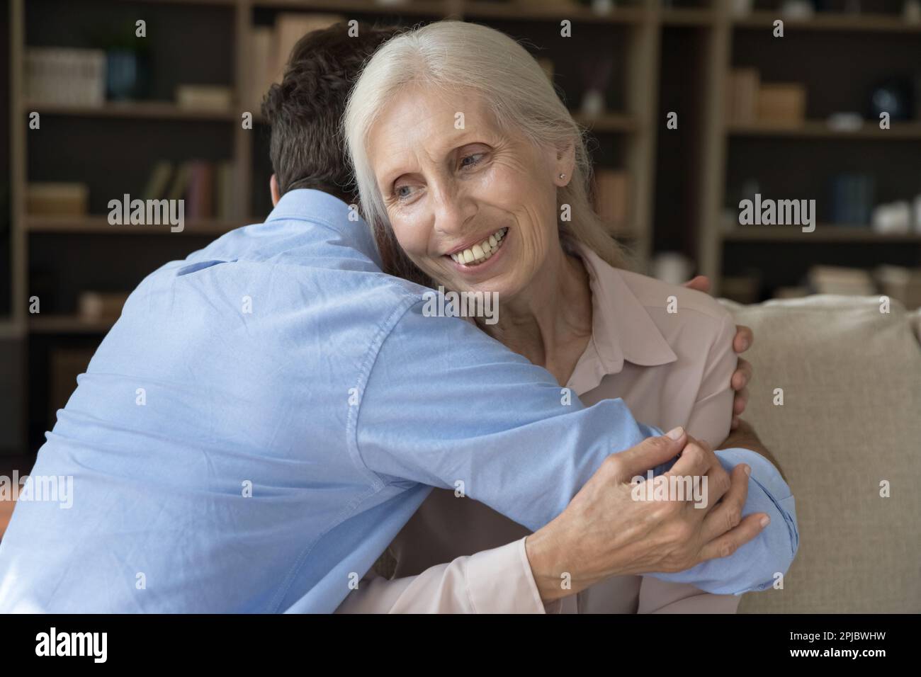 Adult son embracing happy elderly mom on couch, visiting mother Stock ...