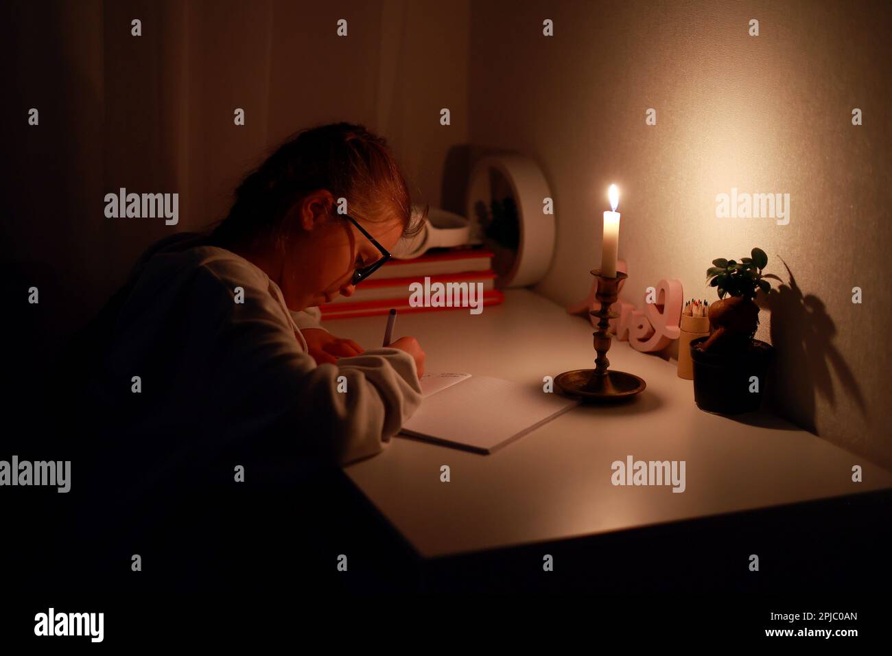 Schoolgirl uses candlelight to writes and reads in darkness without ...