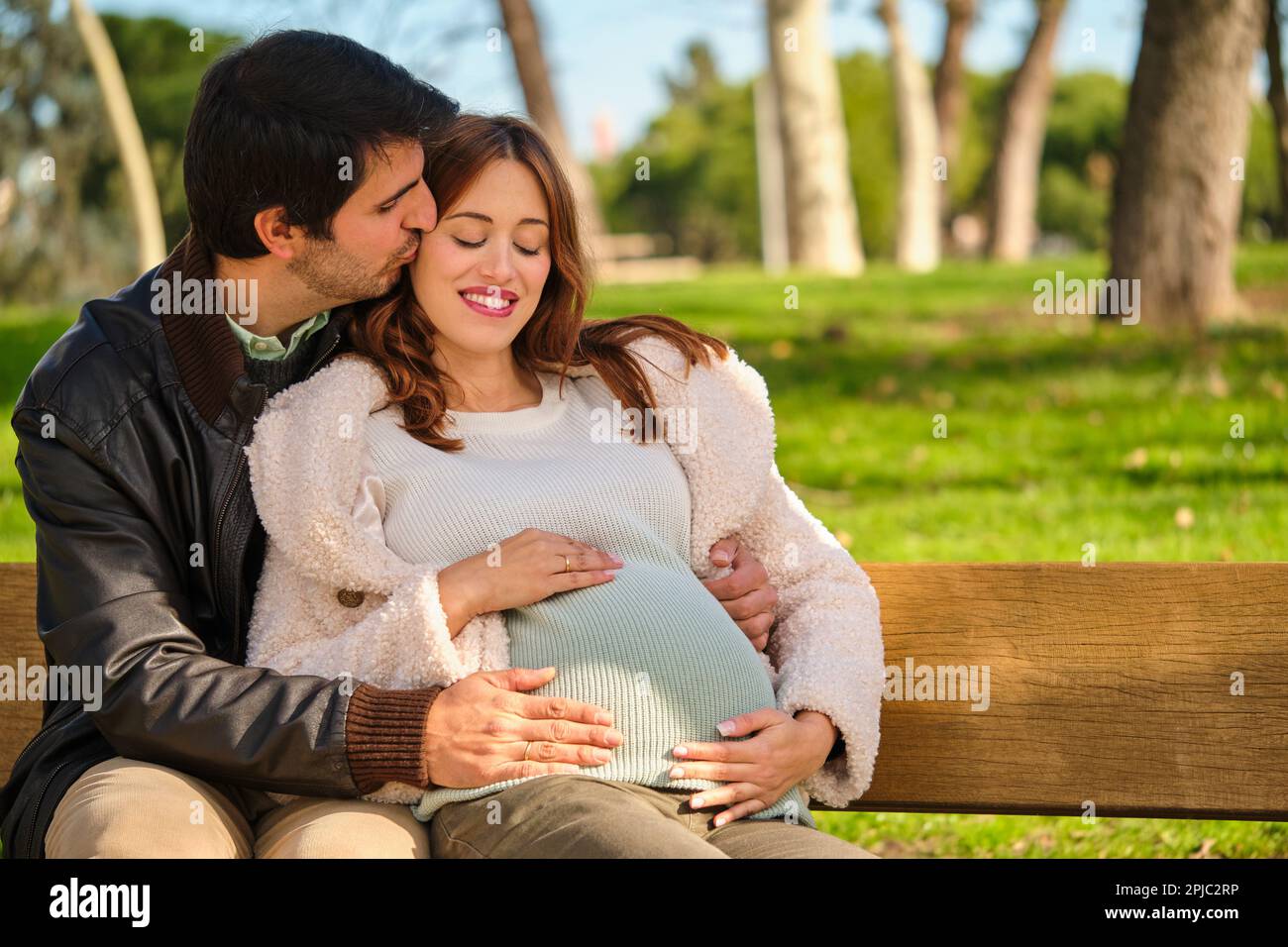 Man Kissing His Happy Pregnant Wife Couple Embracing And Touching Her
