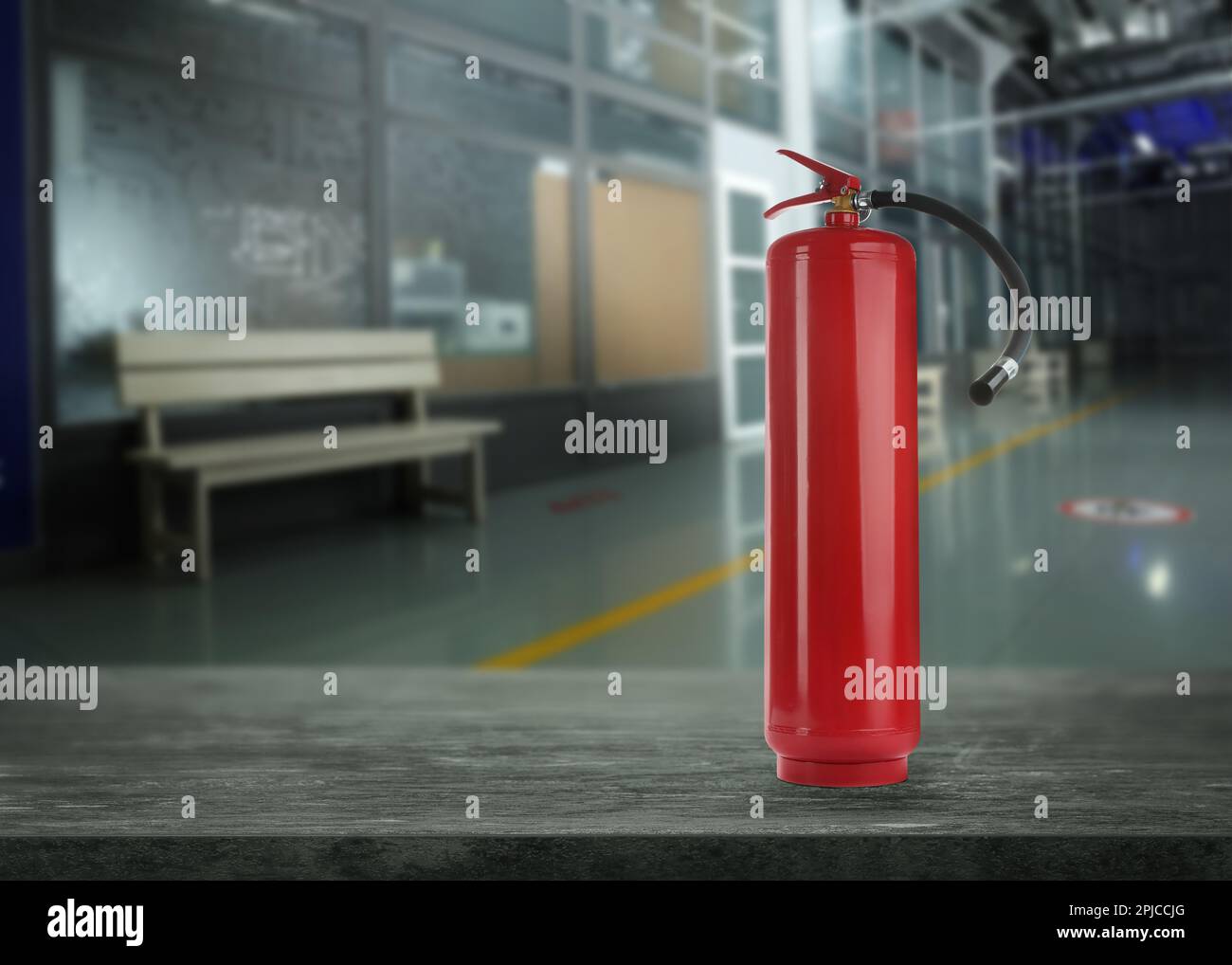 Fire extinguisher on stone table in office corridor. Space for text ...