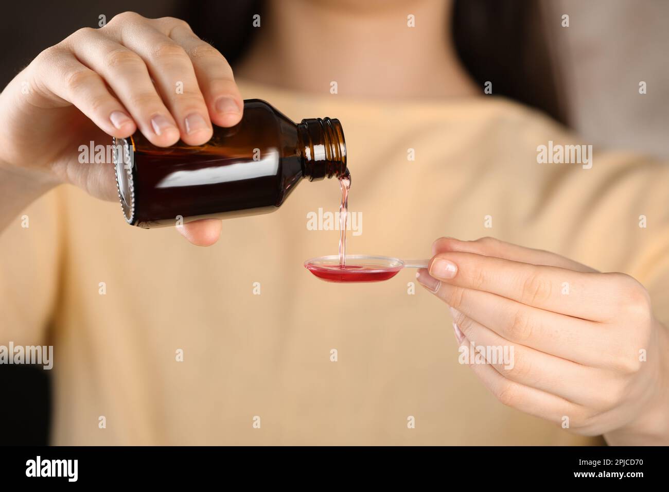 Woman pouring cough syrup into dosing spoon, closeup Stock Photo - Alamy