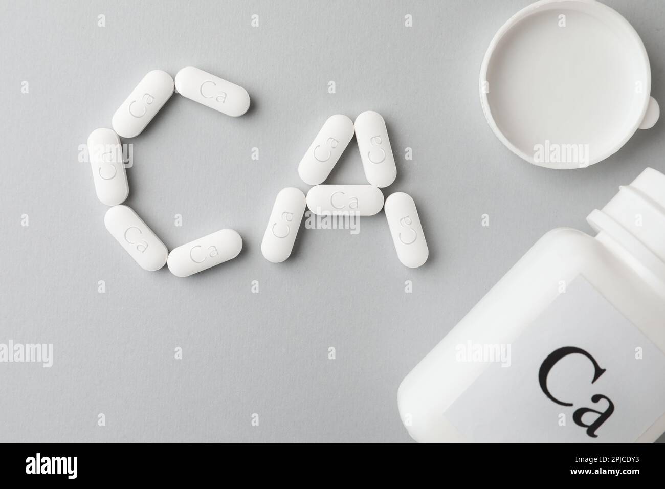 Calcium supplement pills and jar on light grey background, flat lay ...