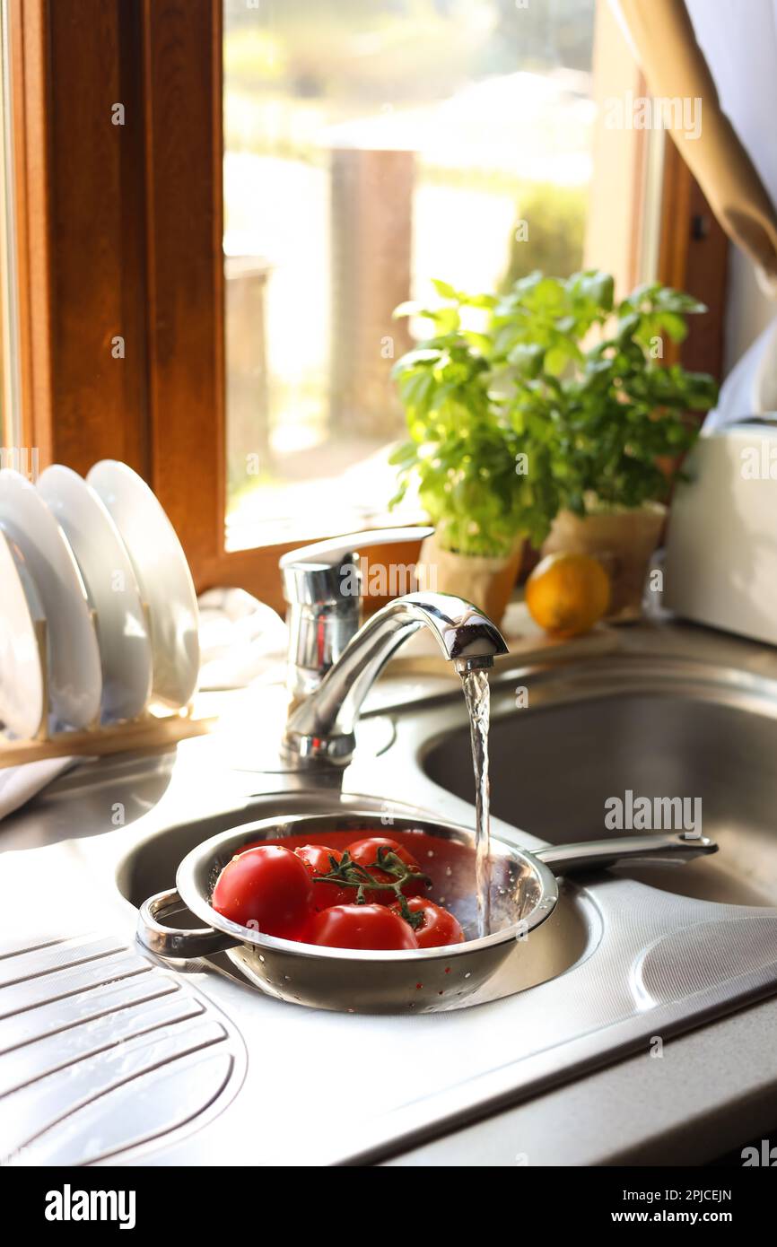 Fresh ripe tomatoes under tap water in kitchen sink Stock Photo - Alamy